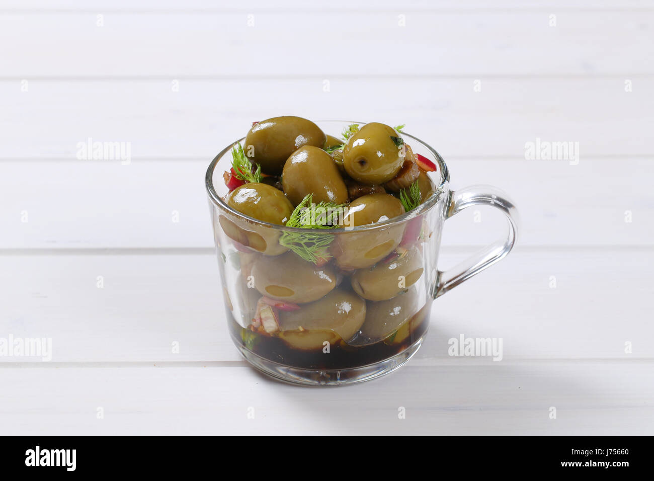cup of marinated green olives on white wooden background Stock Photo ...
