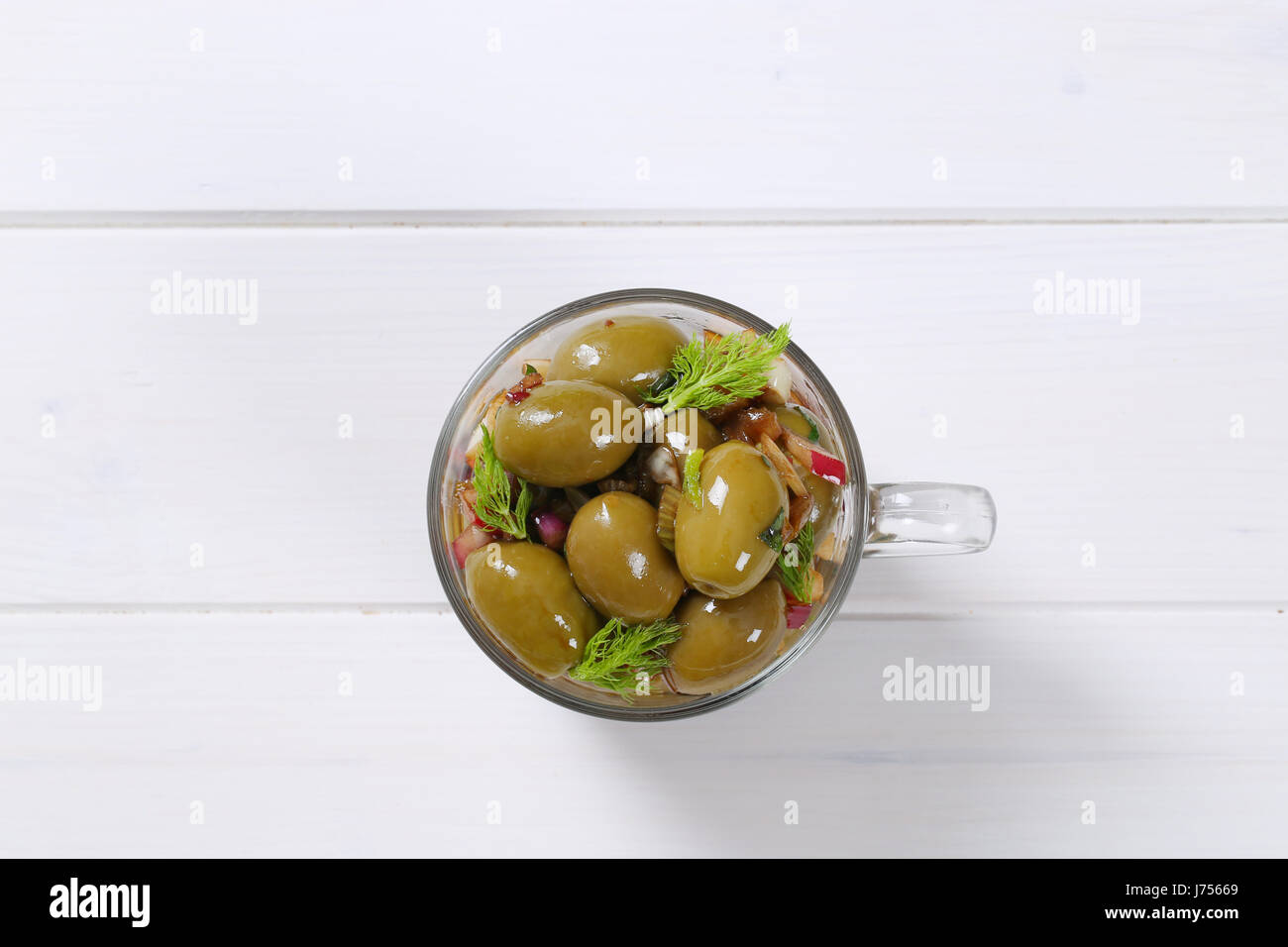 cup of marinated green olives on white wooden background Stock Photo ...