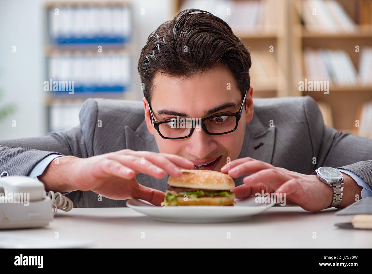 Hungry funny businessman eating junk food sandwich Stock Photo - Alamy