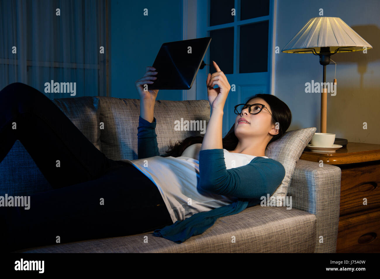 beautiful girl holding pad computer lying on the sofa and touching the ...