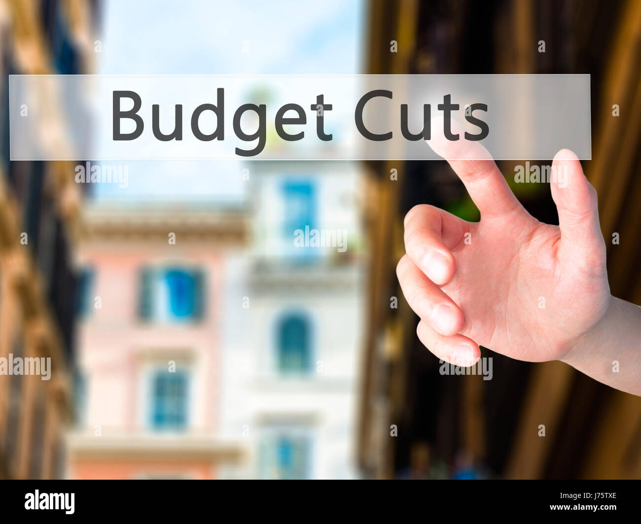 Budget Cuts - Hand pressing a button on blurred background concept ...