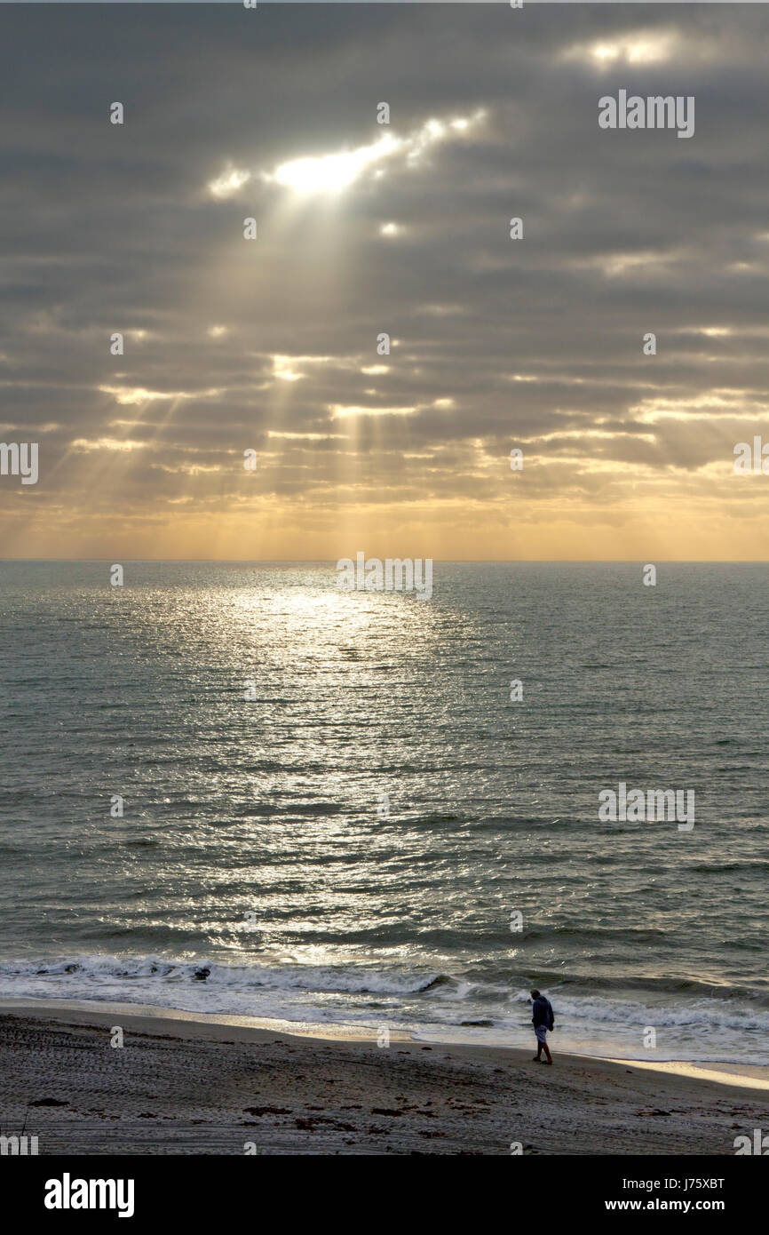 Light rays pour down breaking through dark clouds onto a calm sea ...