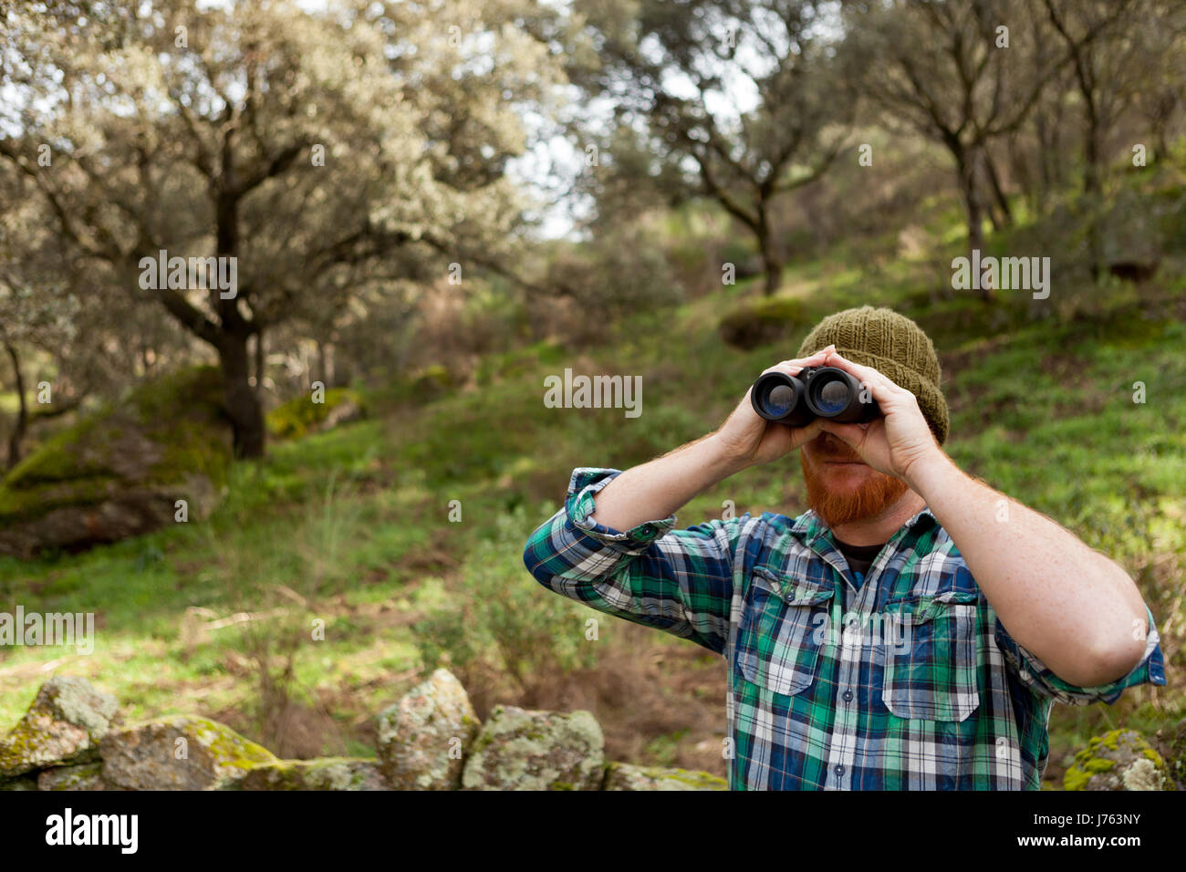 Young Man using binoculars in a green forest Stock Photo - Alamy