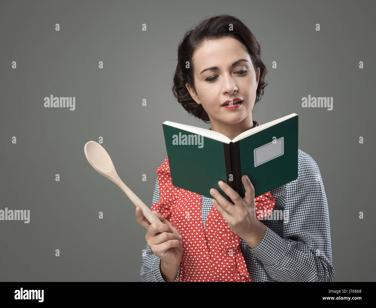 Smiling vintage woman holding an open cookbook and a wooden spoon Stock ...