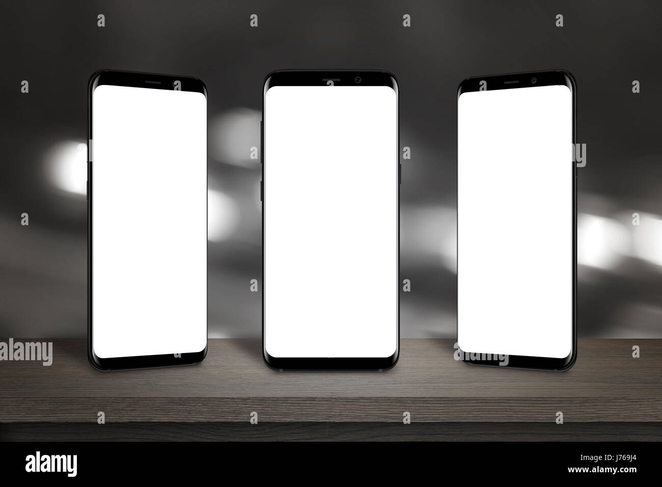 Three mobile phones with isolated screen for mockup on the table. Bokeh ...