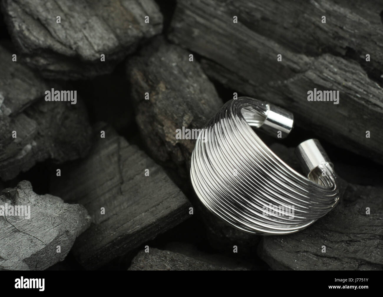 Silver jewelry ring on black coal background Stock Photo - Alamy