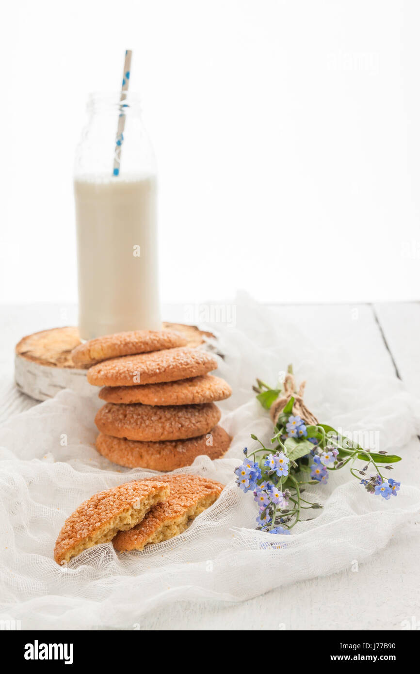 A stack of round shortbread cookies, a bottle of milk and a bouquet of ...