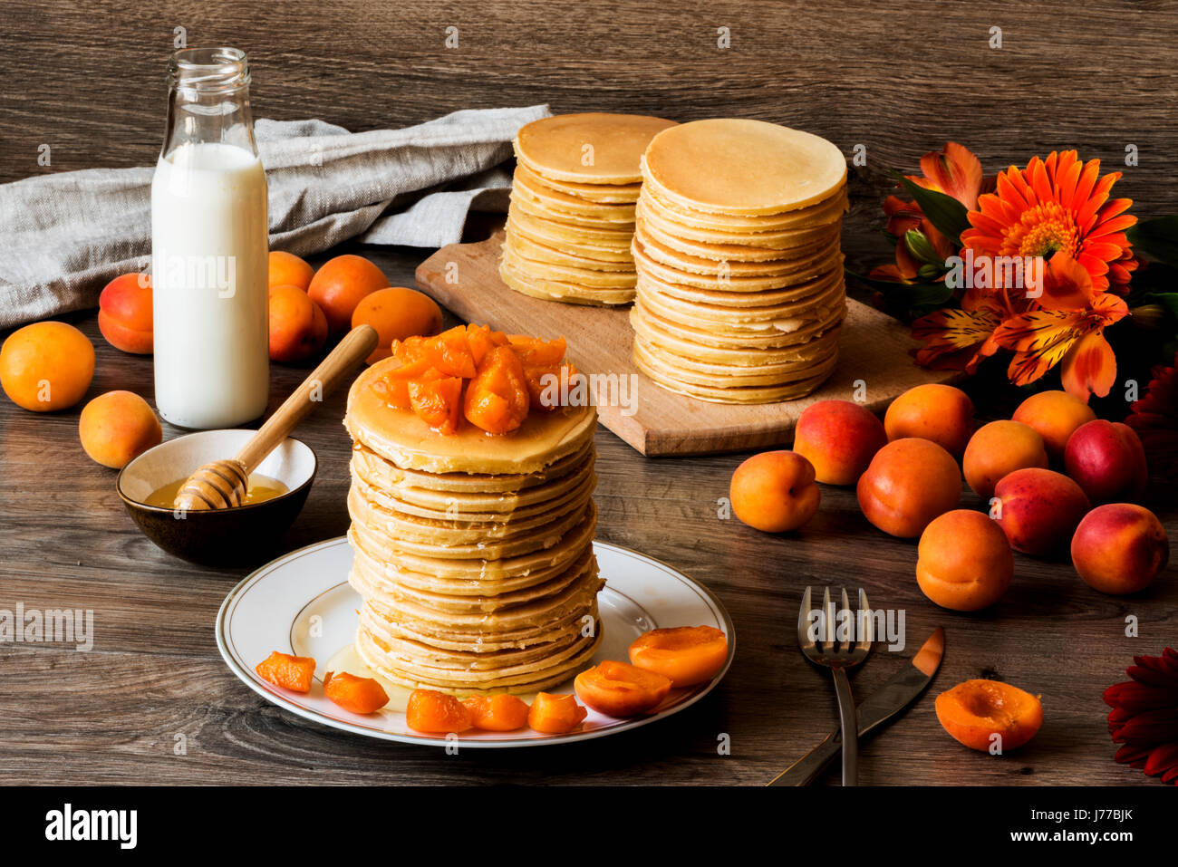 Stack of homemade american pancakes served with honey and apricots on ...