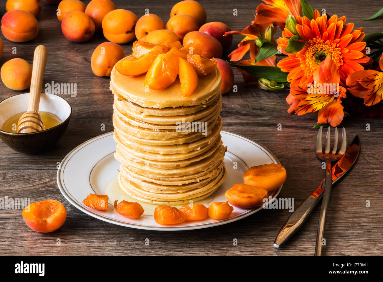 Stack of homemade american pancakes served with honey and apricots on ...