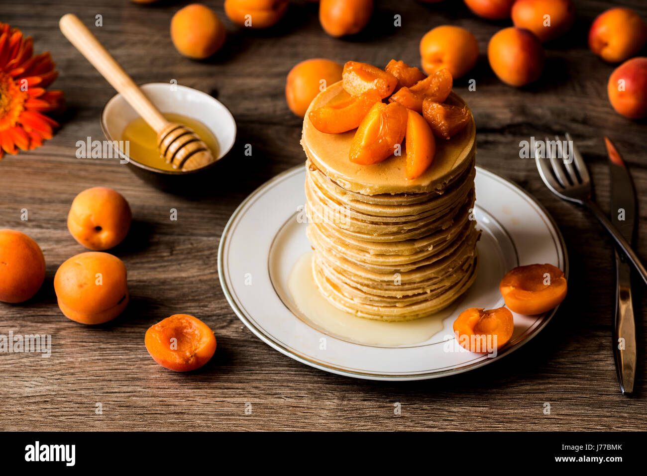 Stack of homemade american pancakes served with honey and apricots on ...