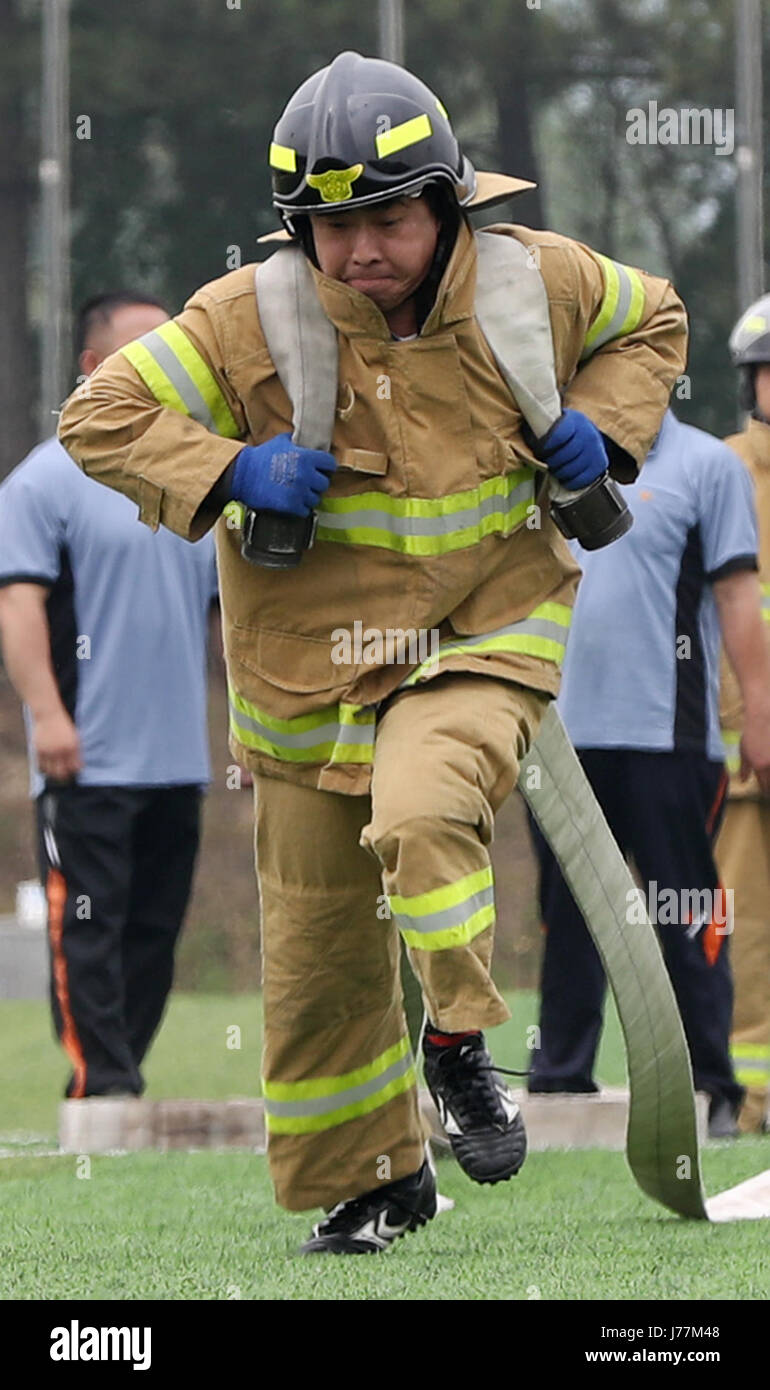 Firefighting skill contest A volunteer firefighter runs with a fire ...