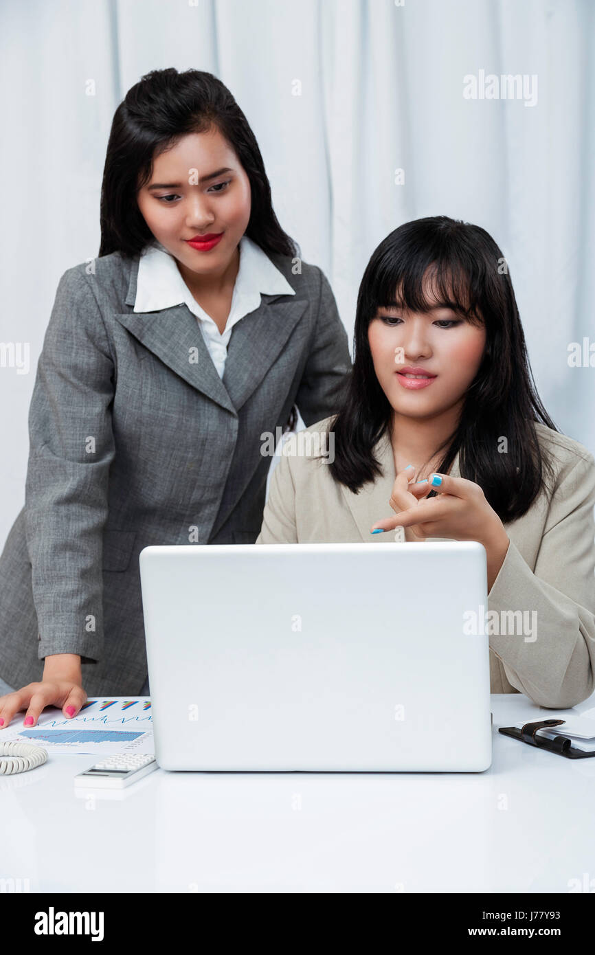 Portrait Of Businesswomen Discussing Work On Computer In Office Stock