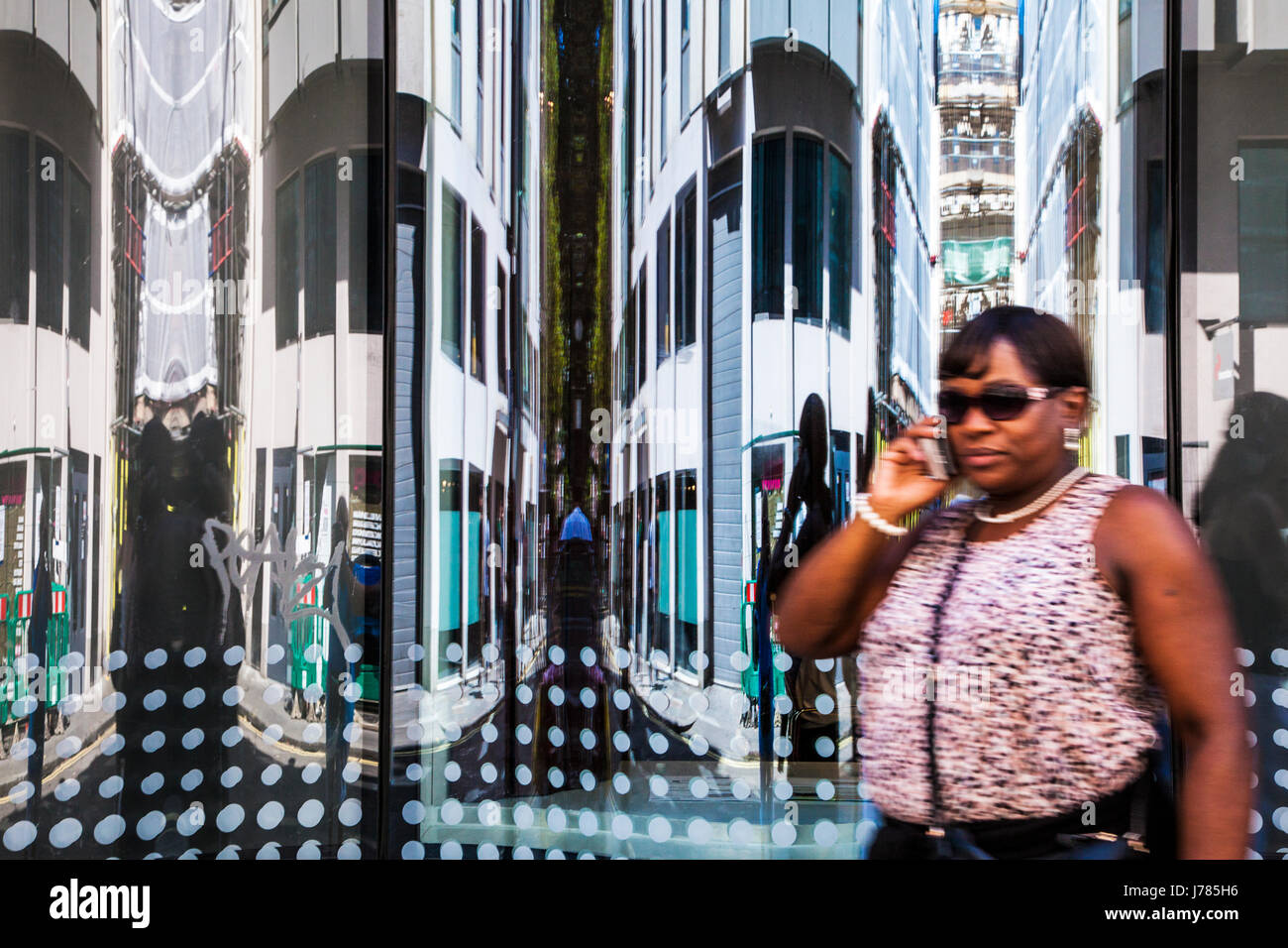 Black woman on mobile phone with distorted reflections in a Soho office ...