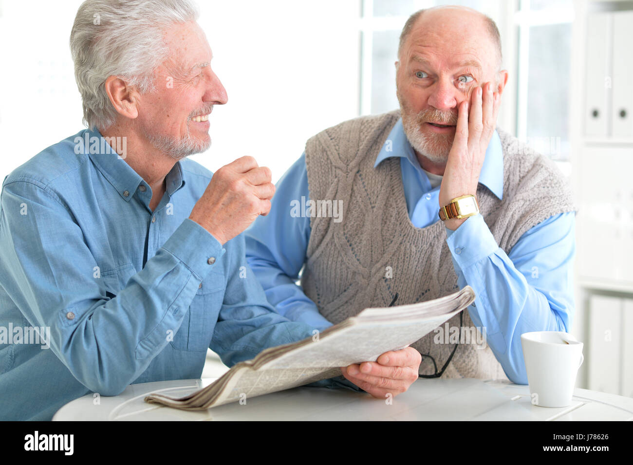 Old men reading a newspaper at a table Stock Photo - Alamy