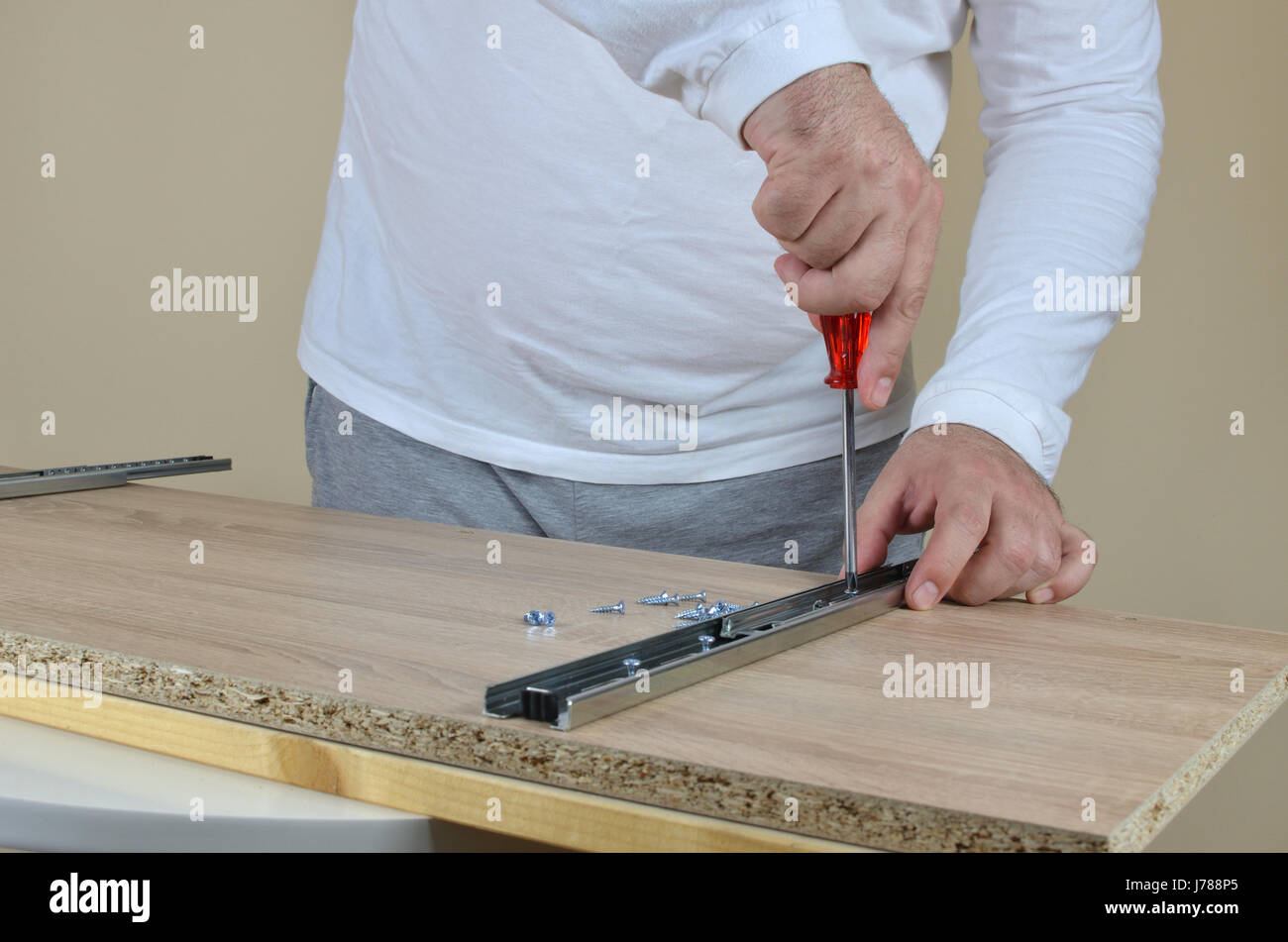 Man holding a screwdriver and installing a rail for drawers Stock Photo ...