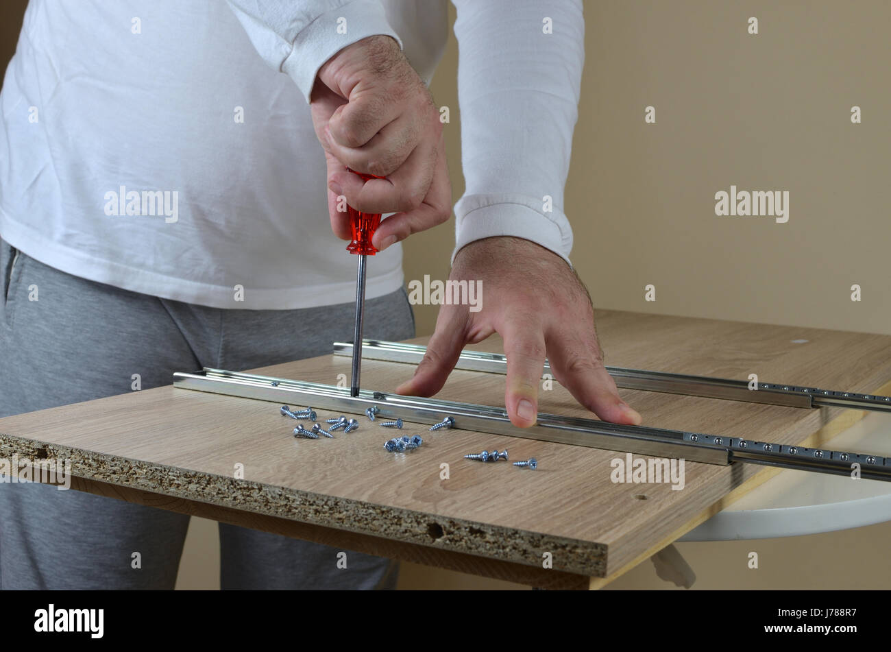 Man installing rails with a screwdriver on an element of a cabinet in ...