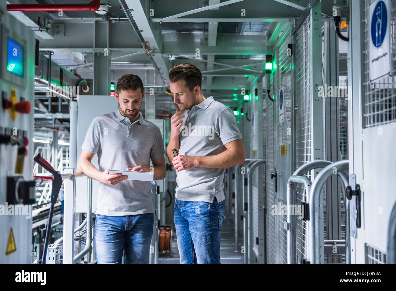 Two men in automatized high rack warehouse looking at tablet Stock ...