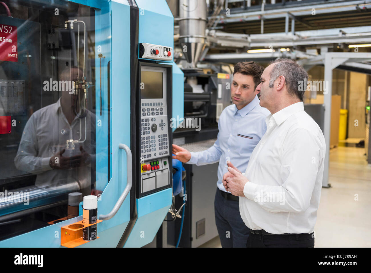 Two men looking at machine in factory shop floor Stock Photo - Alamy