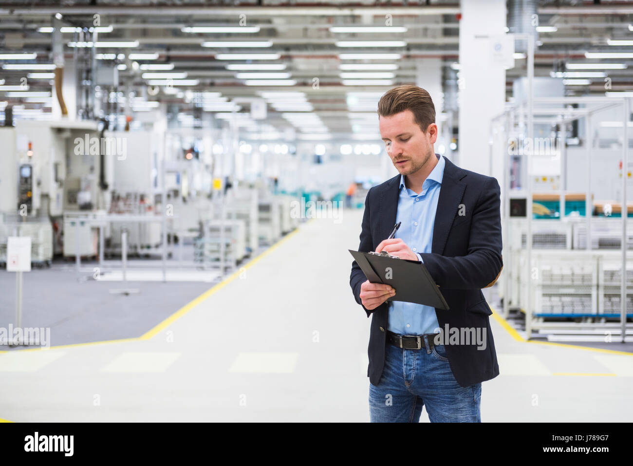 Man standing in factory shop floor taking notes Stock Photo - Alamy