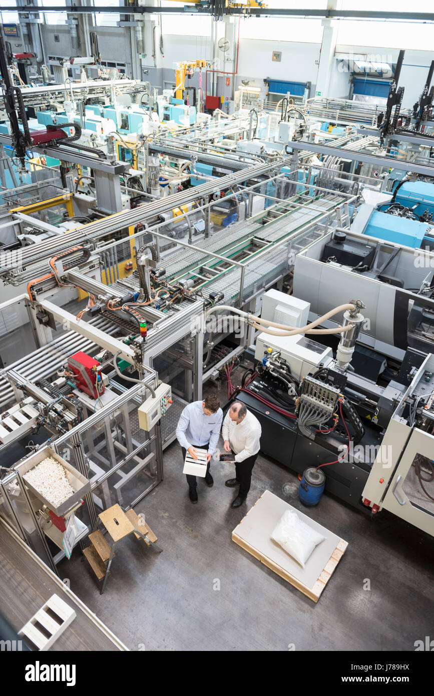 Top view of two men in factory shop floor talking about product Stock ...