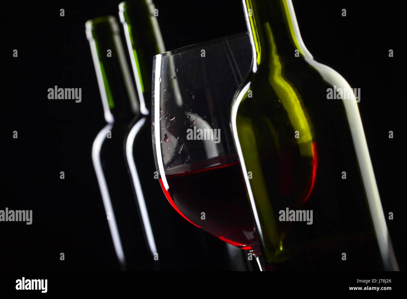 Bottles and glass of red wine on a black background . Selective focus ...