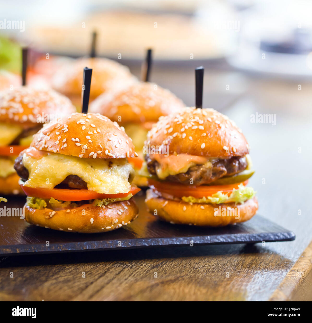 Burgers stuffed with delicious toppings on wooden table in restaurant ...