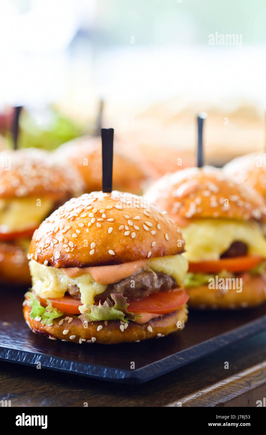 Burgers stuffed with delicious toppings on wooden table in restaurant ...