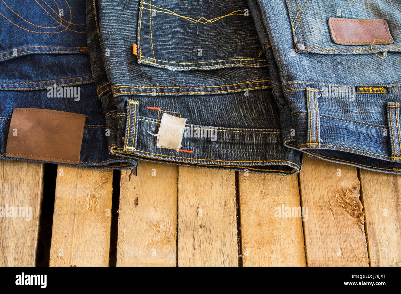 three of jeans with wood background Stock Photo - Alamy