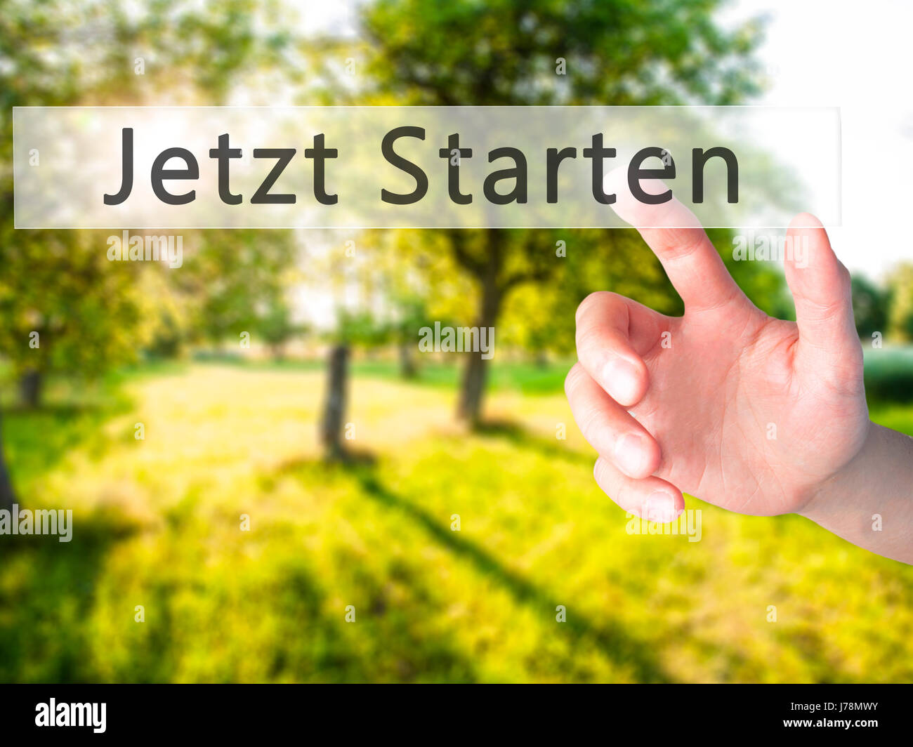 Jetzt Starten (Start Now in German) - Hand pressing a button on blurred ...