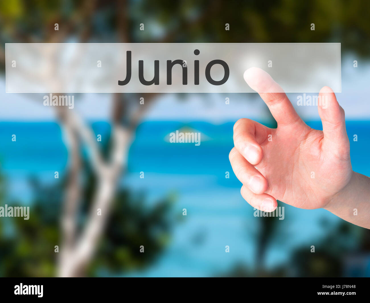 Junio (June in Spanish) - Hand pressing a button on blurred background ...