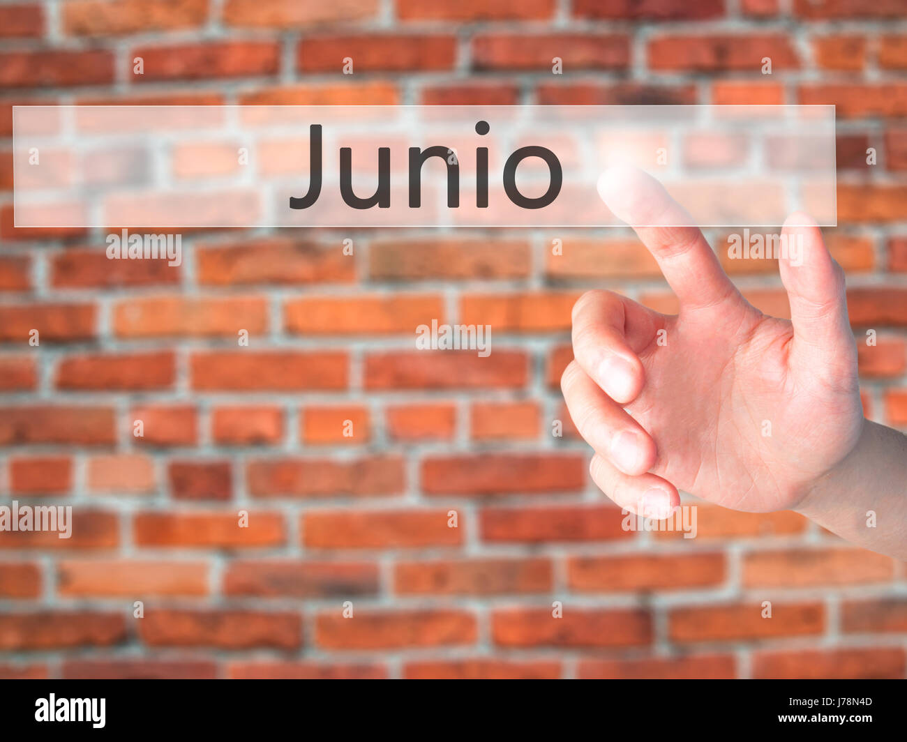 Junio (June in Spanish) - Hand pressing a button on blurred background ...