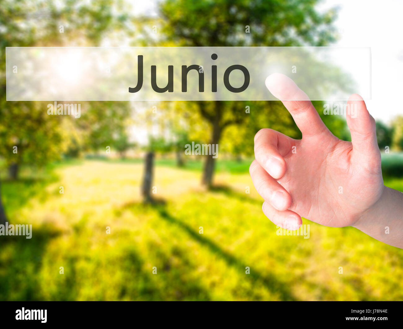 Junio (June in Spanish) - Hand pressing a button on blurred background ...