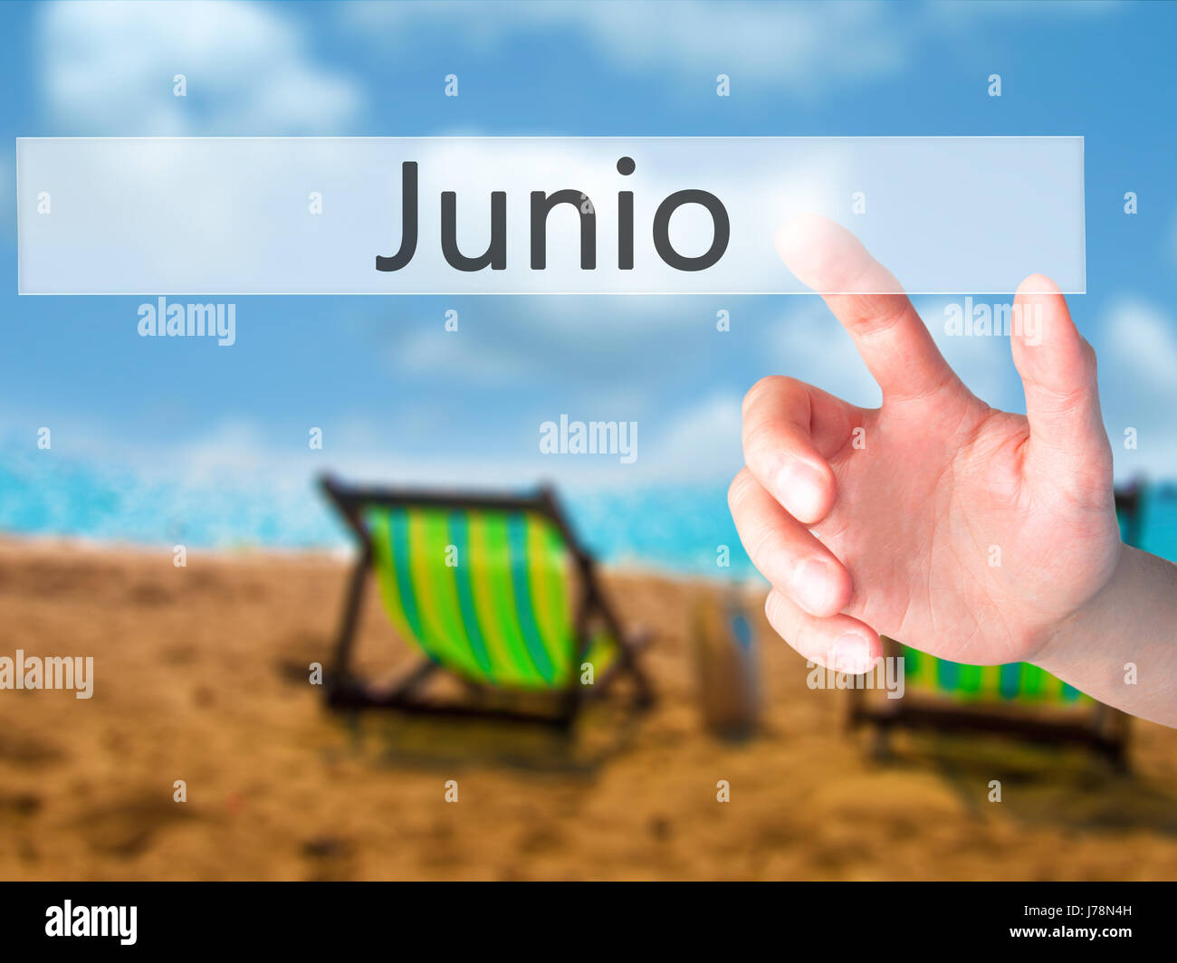 Junio (June in Spanish) - Hand pressing a button on blurred background ...