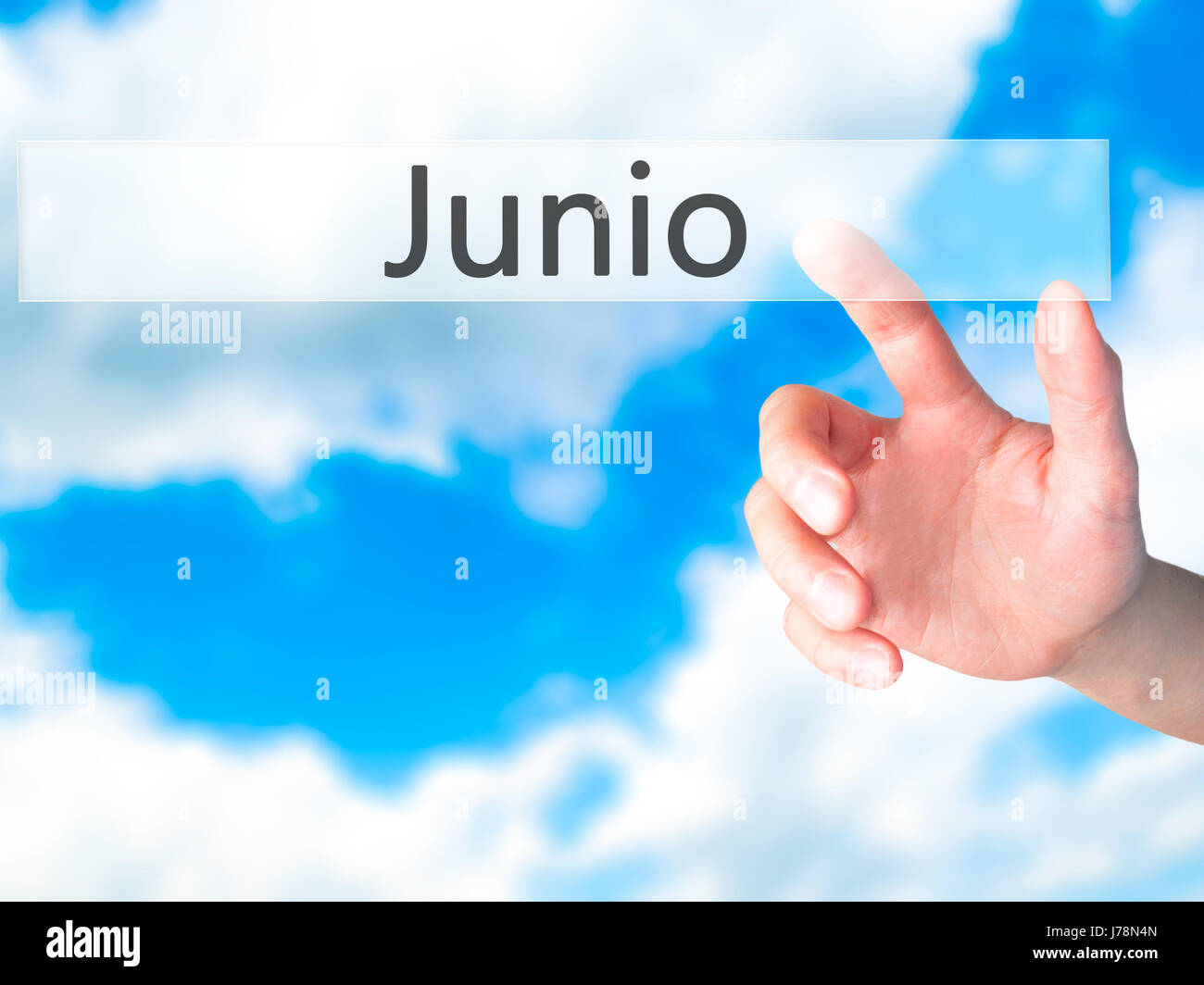 Junio (June in Spanish) - Hand pressing a button on blurred background ...