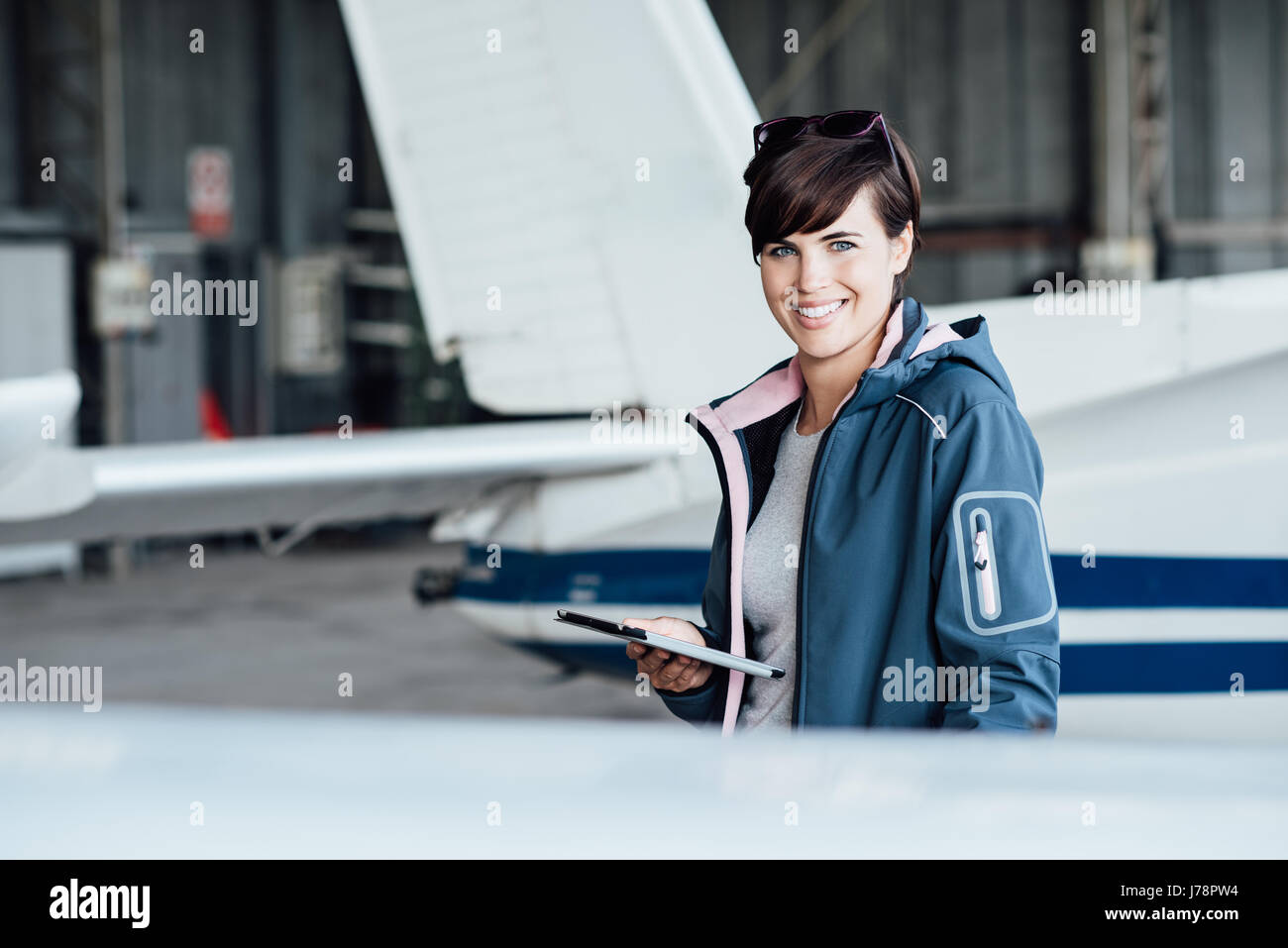 Smiling female pilot connecting with a digital tablet and using ...