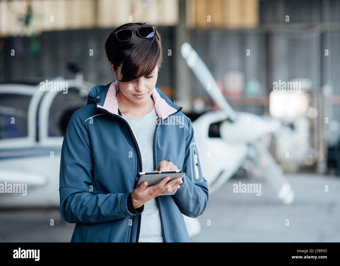 Confident female pilot in the hangar, she is connecting and using ...