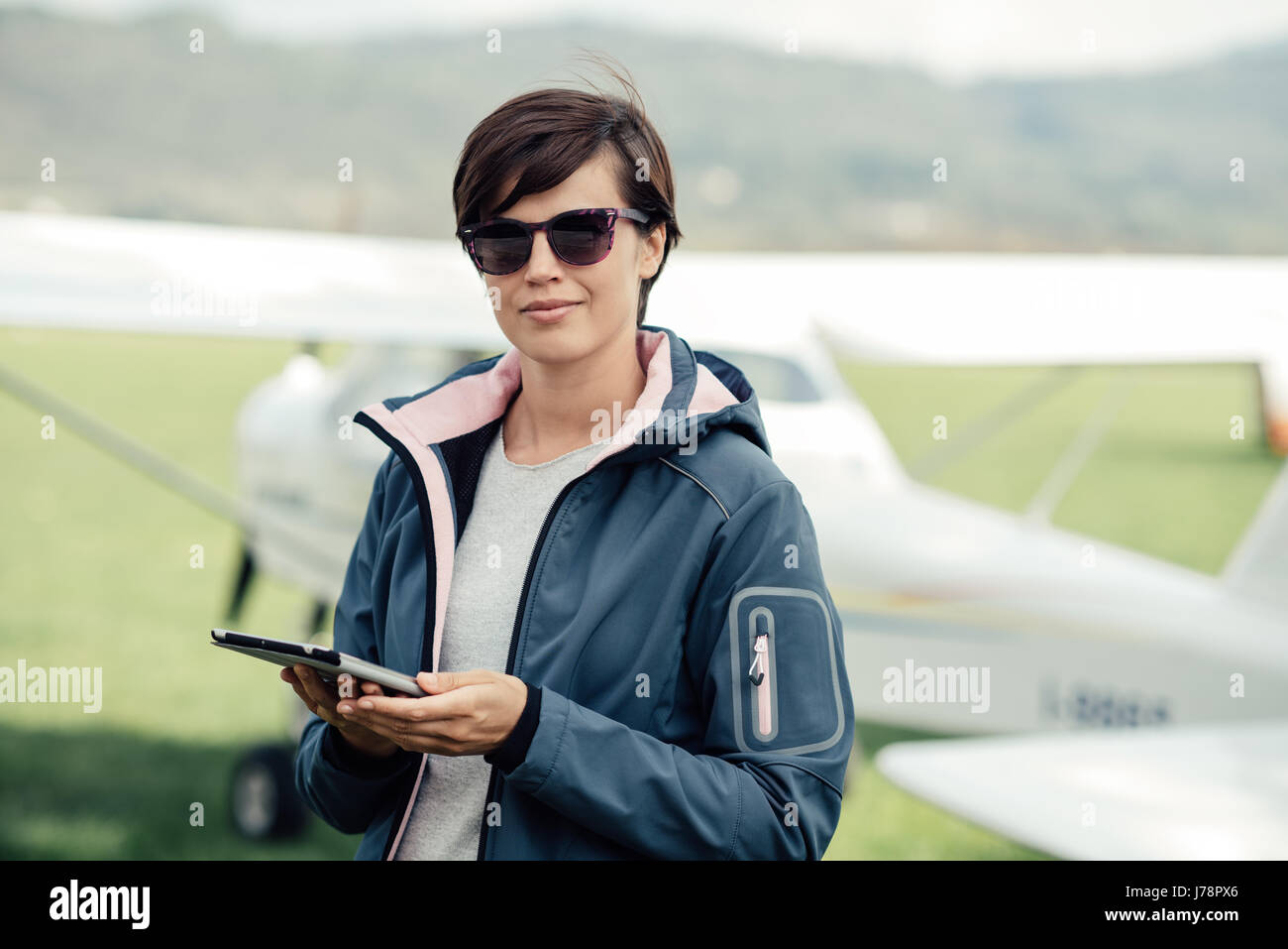 Smiling confident female pilot connecting with a digital tablet and ...