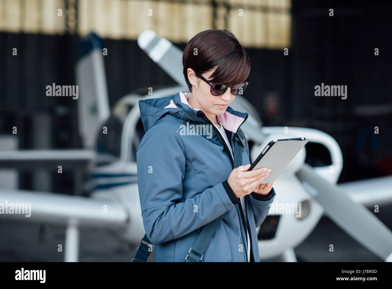 Confident female pilot in the hangar doing a pre-flight preparation ...