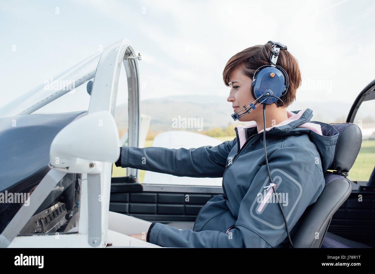 Smiling female pilot in the light aircraft cockpit, she is wearing ...