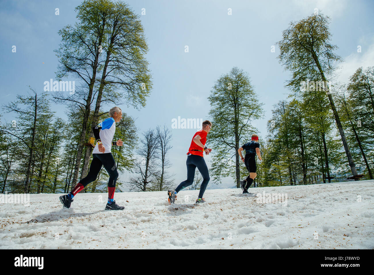 three men runners running snowy mountain trail in race Vertical ...