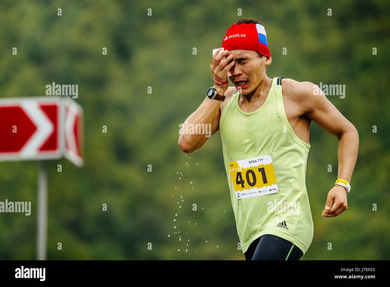 young man runner on water point in hand sponge with water in race ...