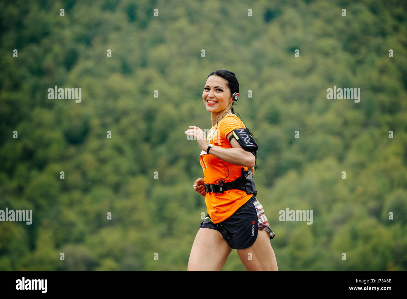 girl runner with music in headphones smiles and running in race Spring ...