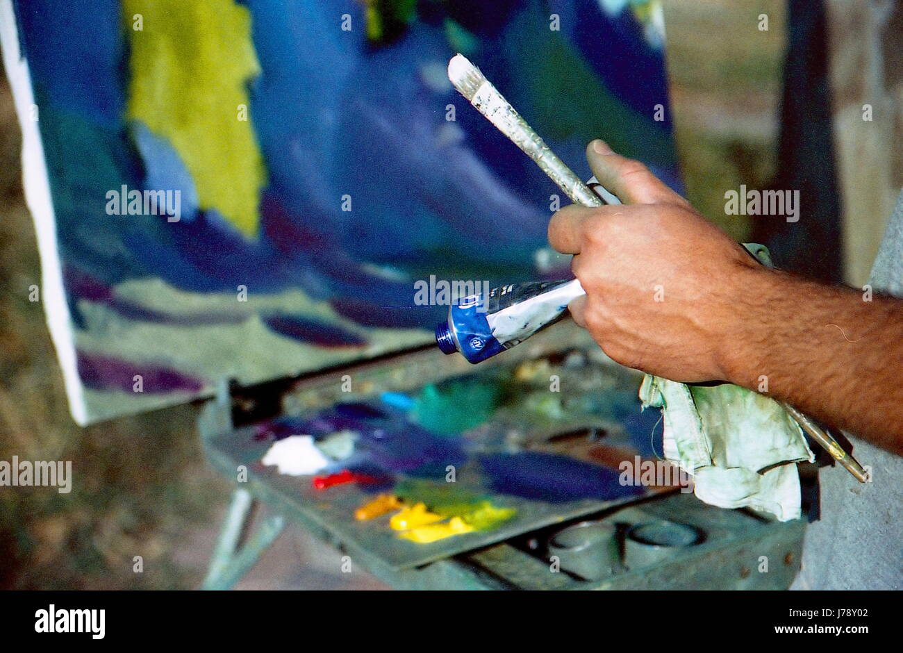 Artist holds in his hand a tube of paint and a paintbrush for drawing ...