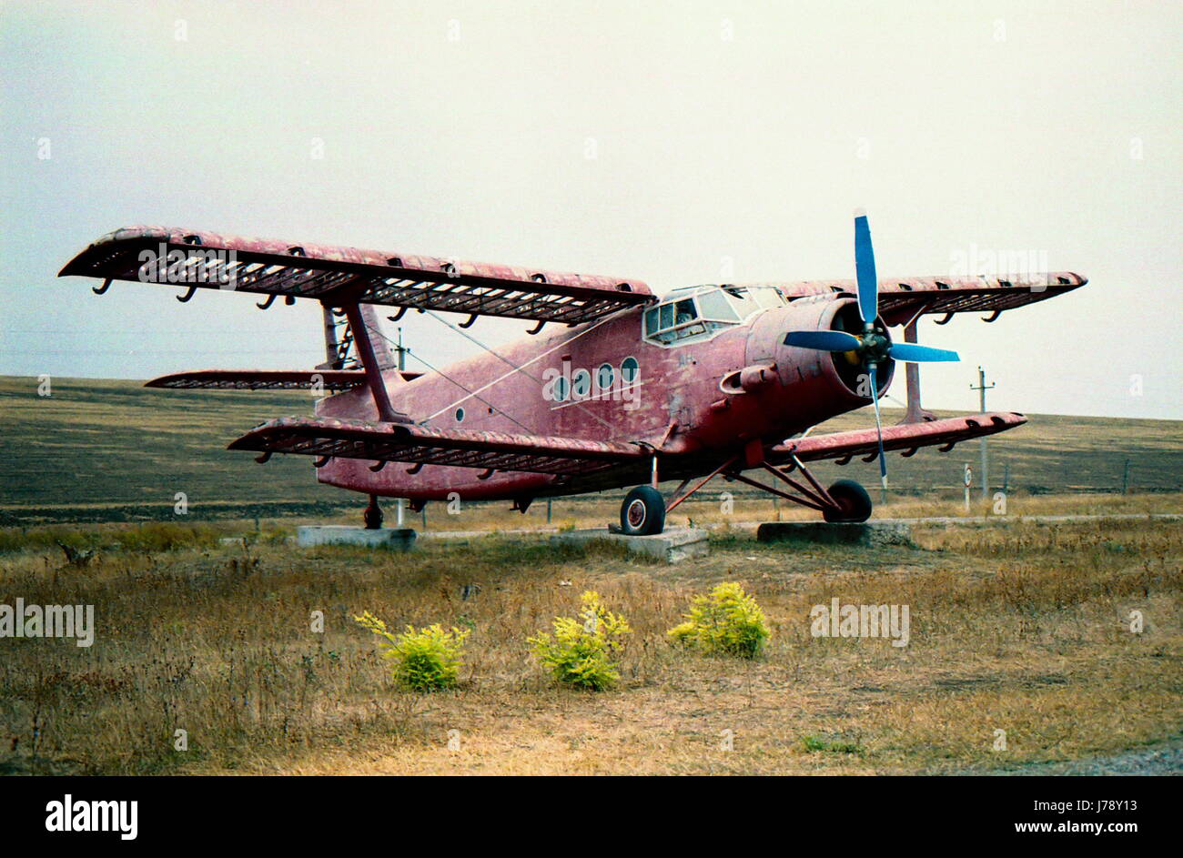 An old, abandoned, red plane stands in the field. The turntable is blue ...