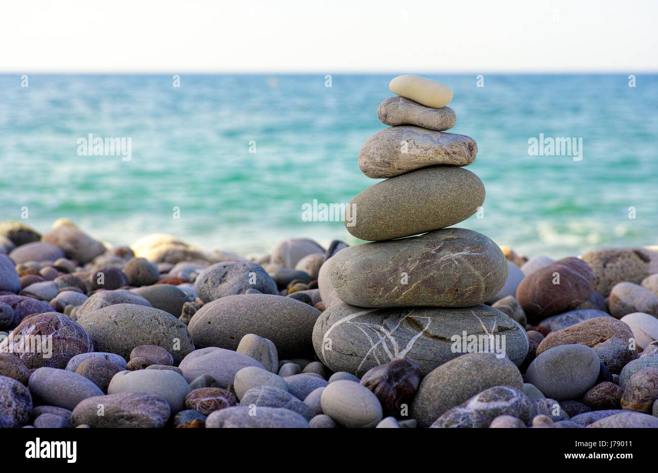 Stack of pebbles on beach against sea. Closeup Stock Photo - Alamy