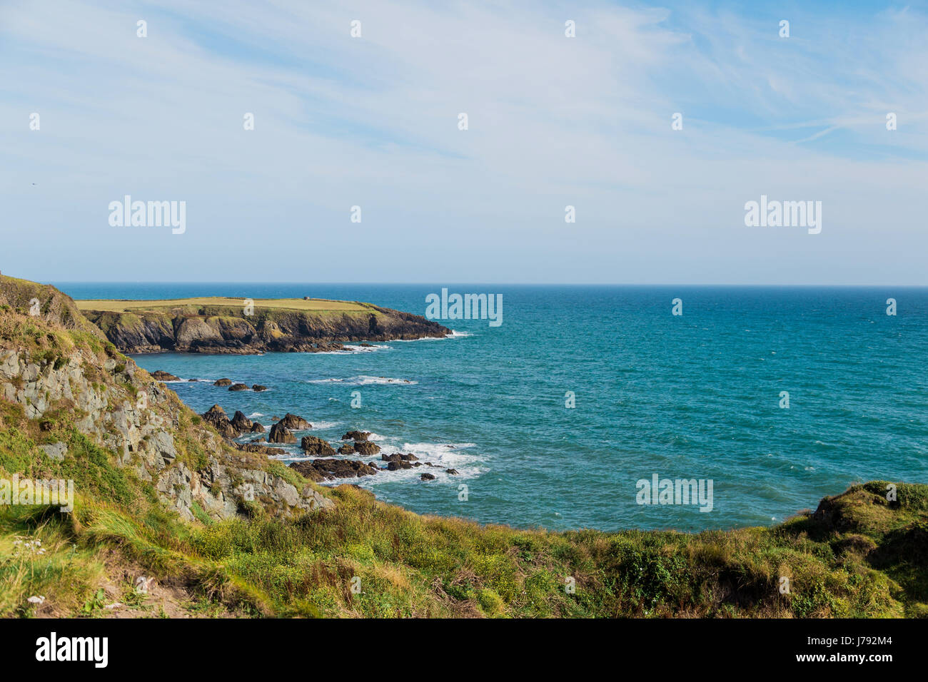 Green grassy cliffs overlooking stark blue Irish Sea in summer Stock ...