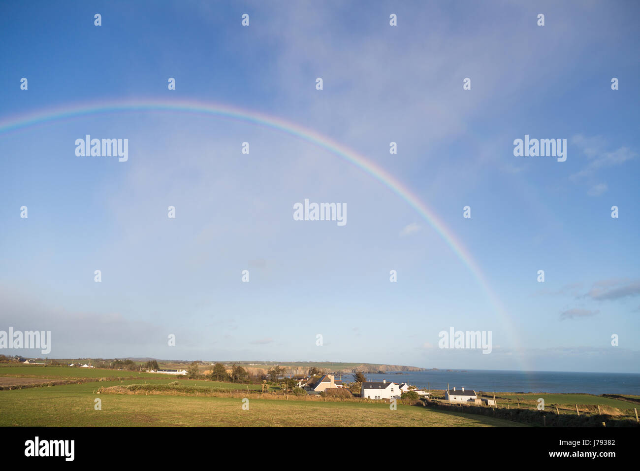 A Rainbow in rural Irish Countryside ending in the Irish Sea Stock ...