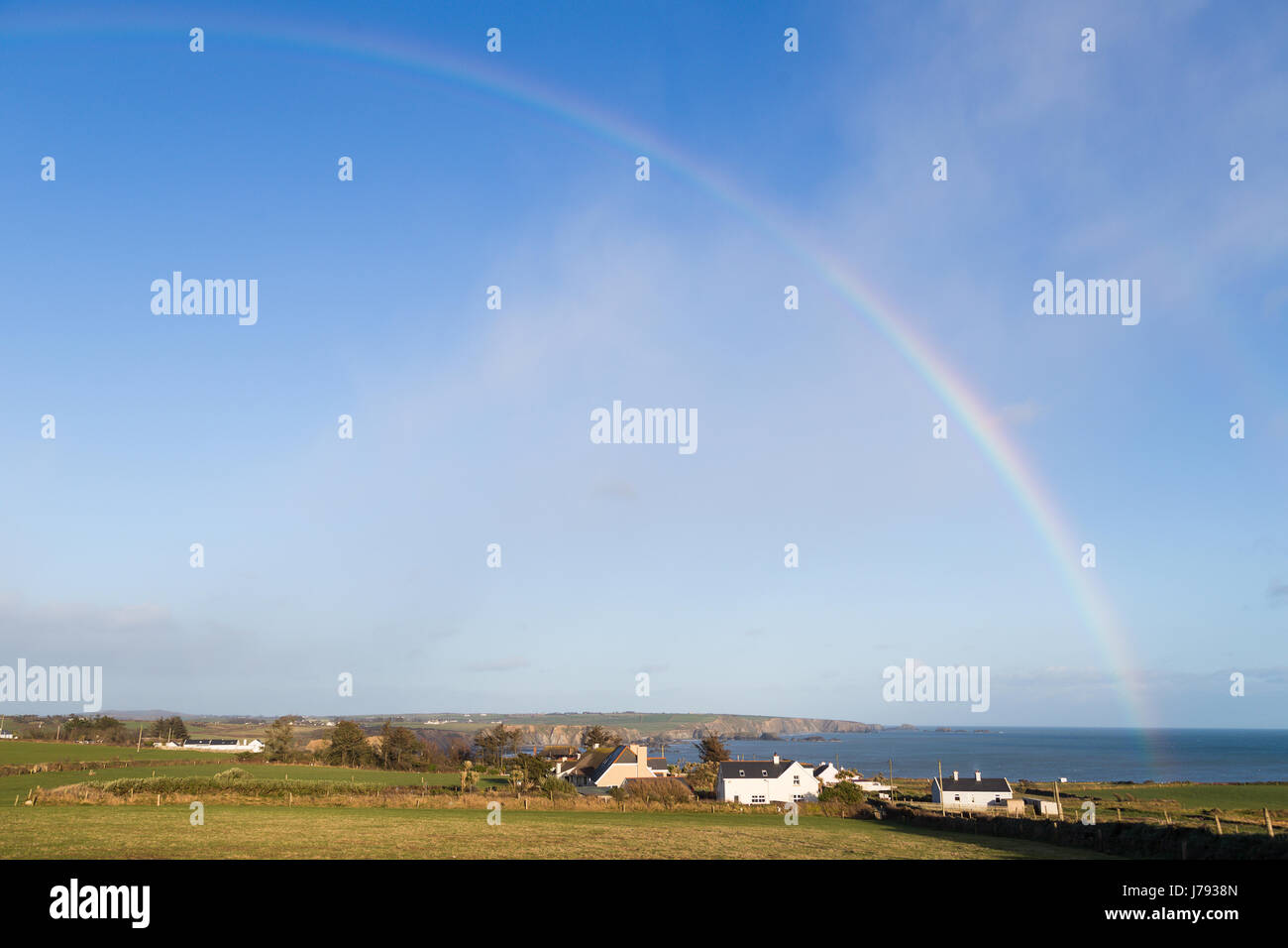 A Rainbow in rural Irish Countryside ending in the Irish Sea Stock ...