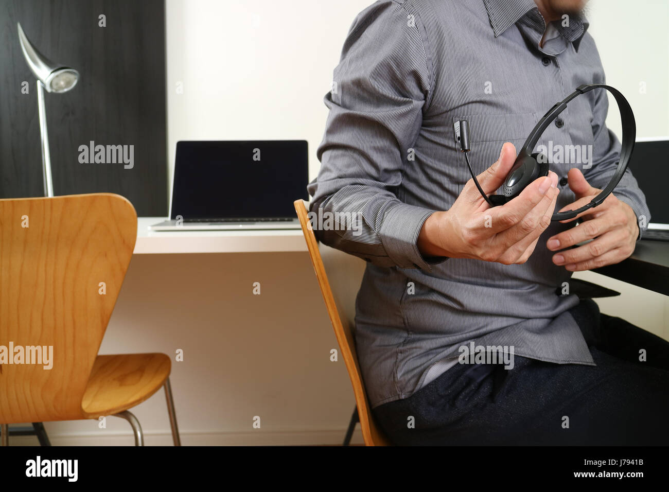 Man using VOIP headset with digital tablet and laptop computer as ...