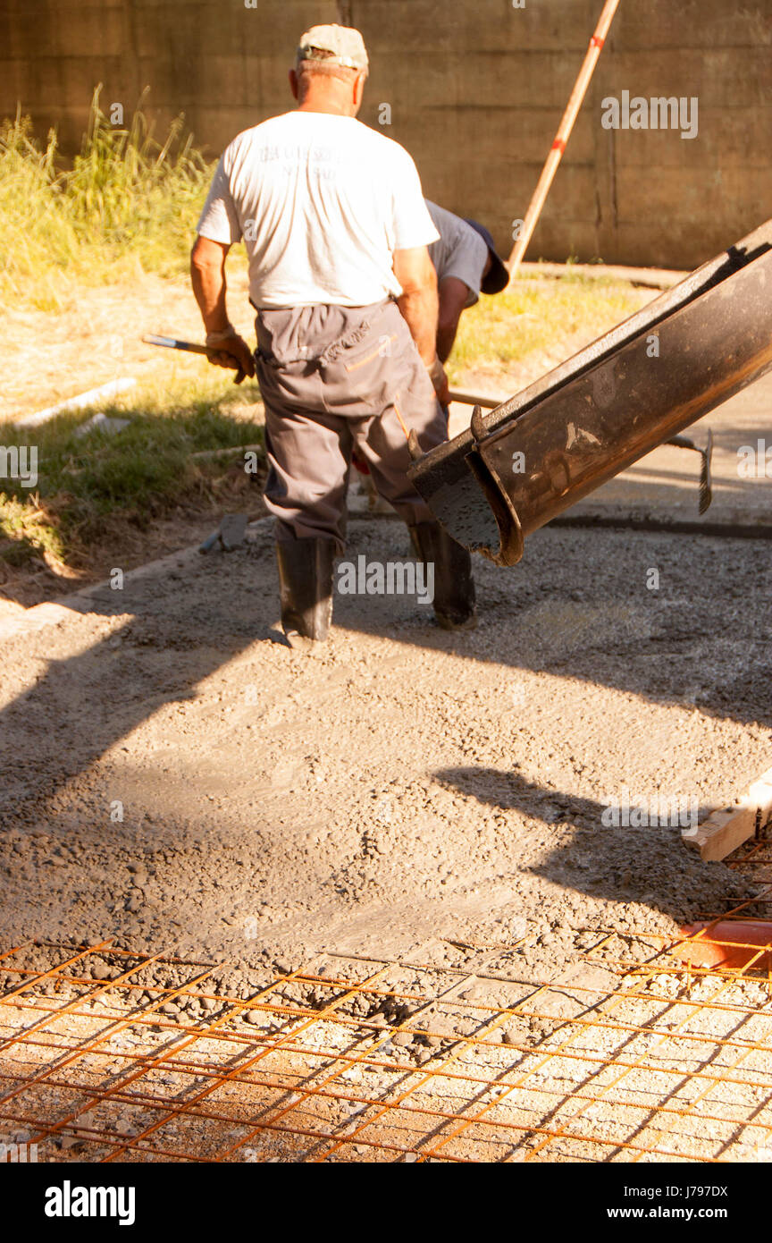 Workers work on concreting parking spaces in front of the house. Mason ...